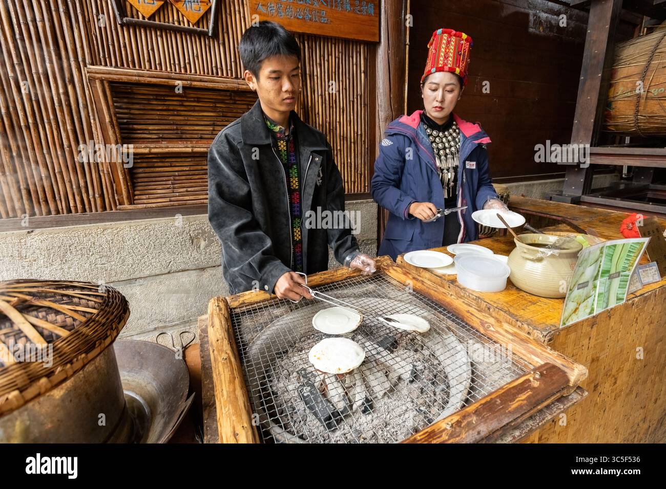 Chinese couple cooking traditional Yunnan rice bread on the charcoals ...