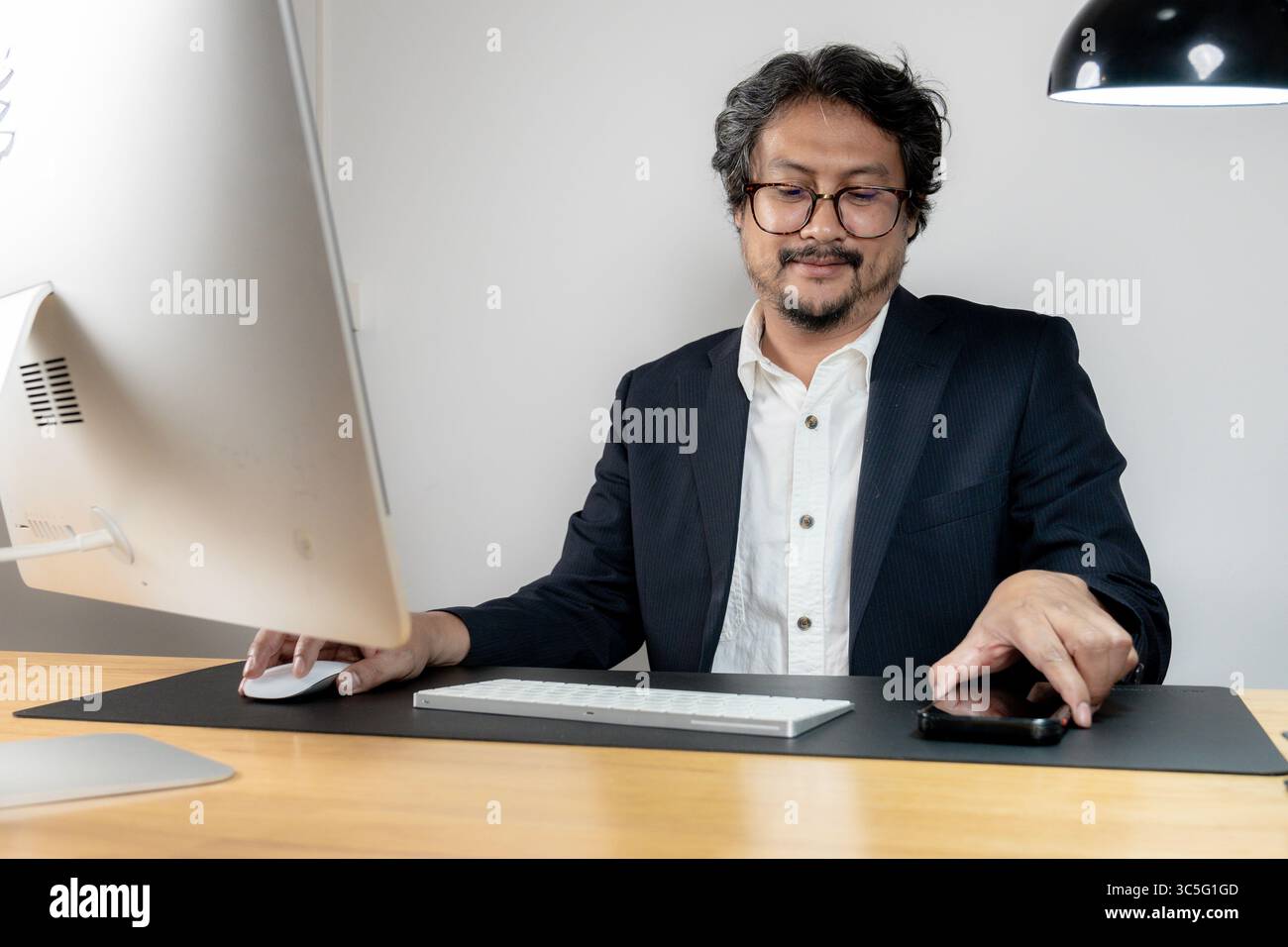 A cheerful male office employee working at his desk in a modern office ...