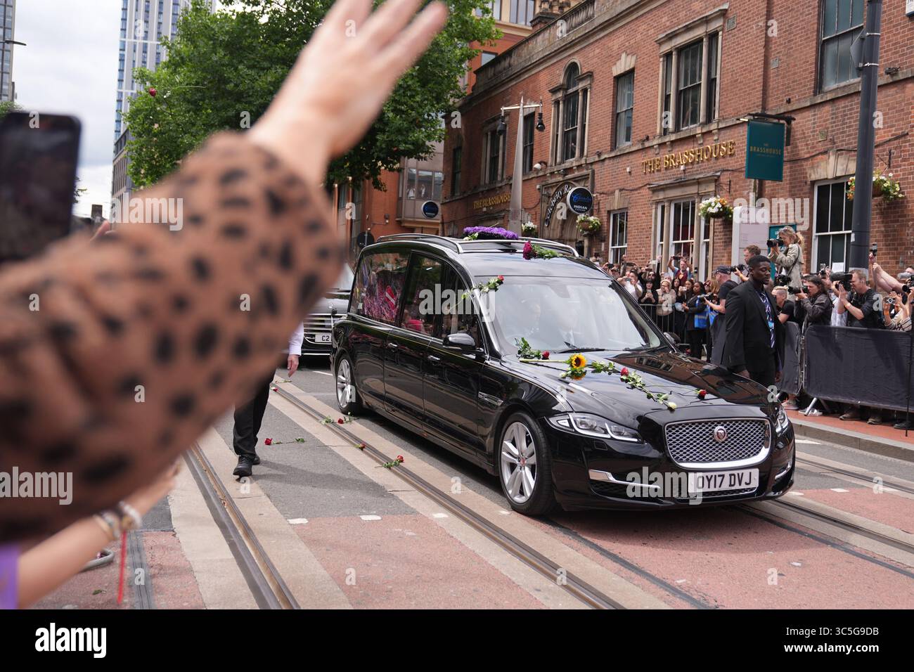 Fans watch on as the hearse carrying the body of Ozzy Osbourne is seen ...