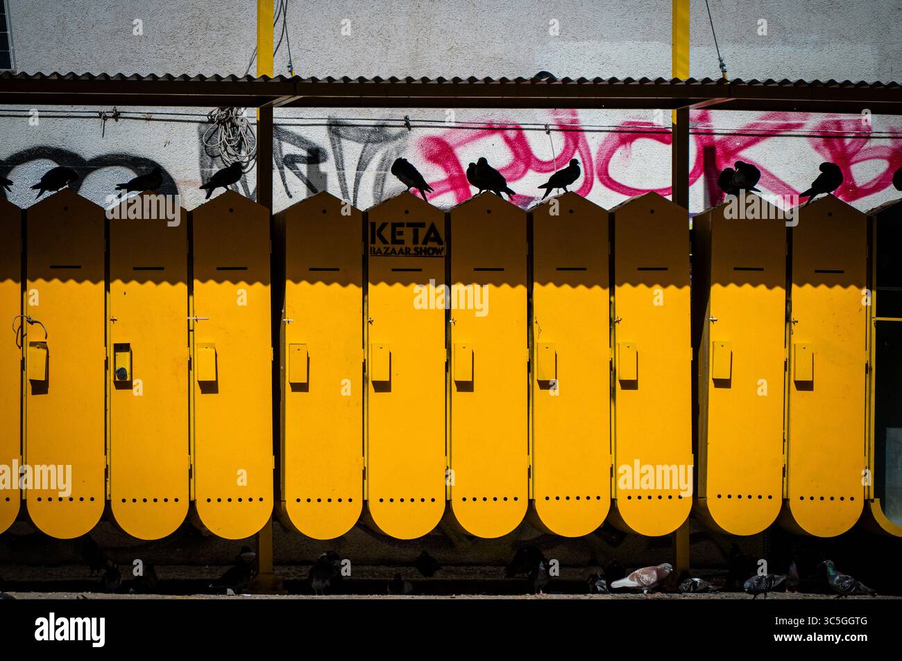 Row of bright yellow lockers with graffiti on top in an urban setting ...