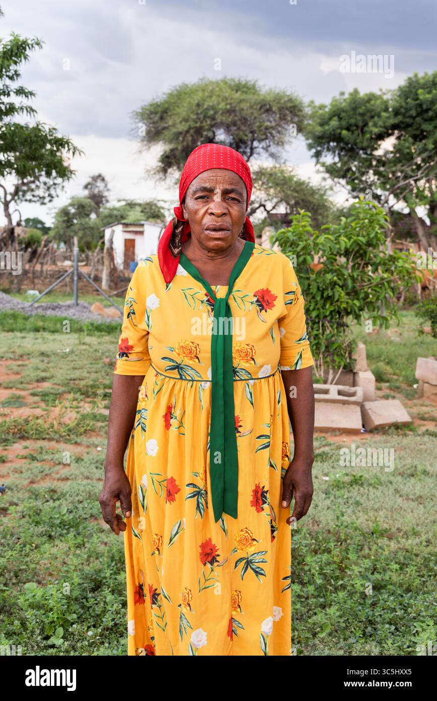 African village, portrait single African old woman standing in the yard ...