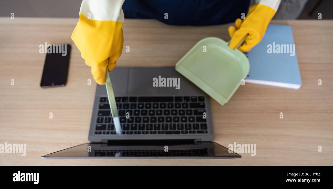 Cleaning Technology. Person using a dustpan and brush to clean laptop ...
