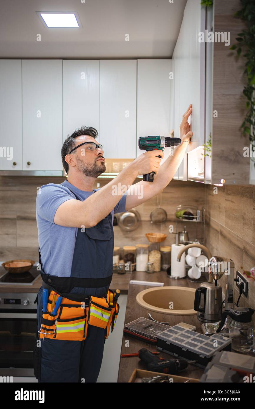 Handyman installing kitchen cabinets using a cordless screwdriver Stock ...