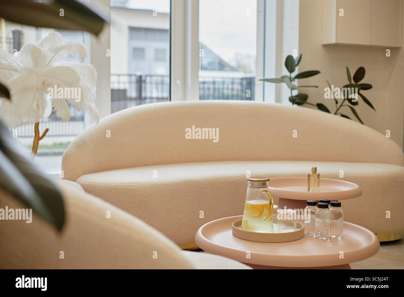 Modern waiting area featuring curved beige sofa and round tables ...