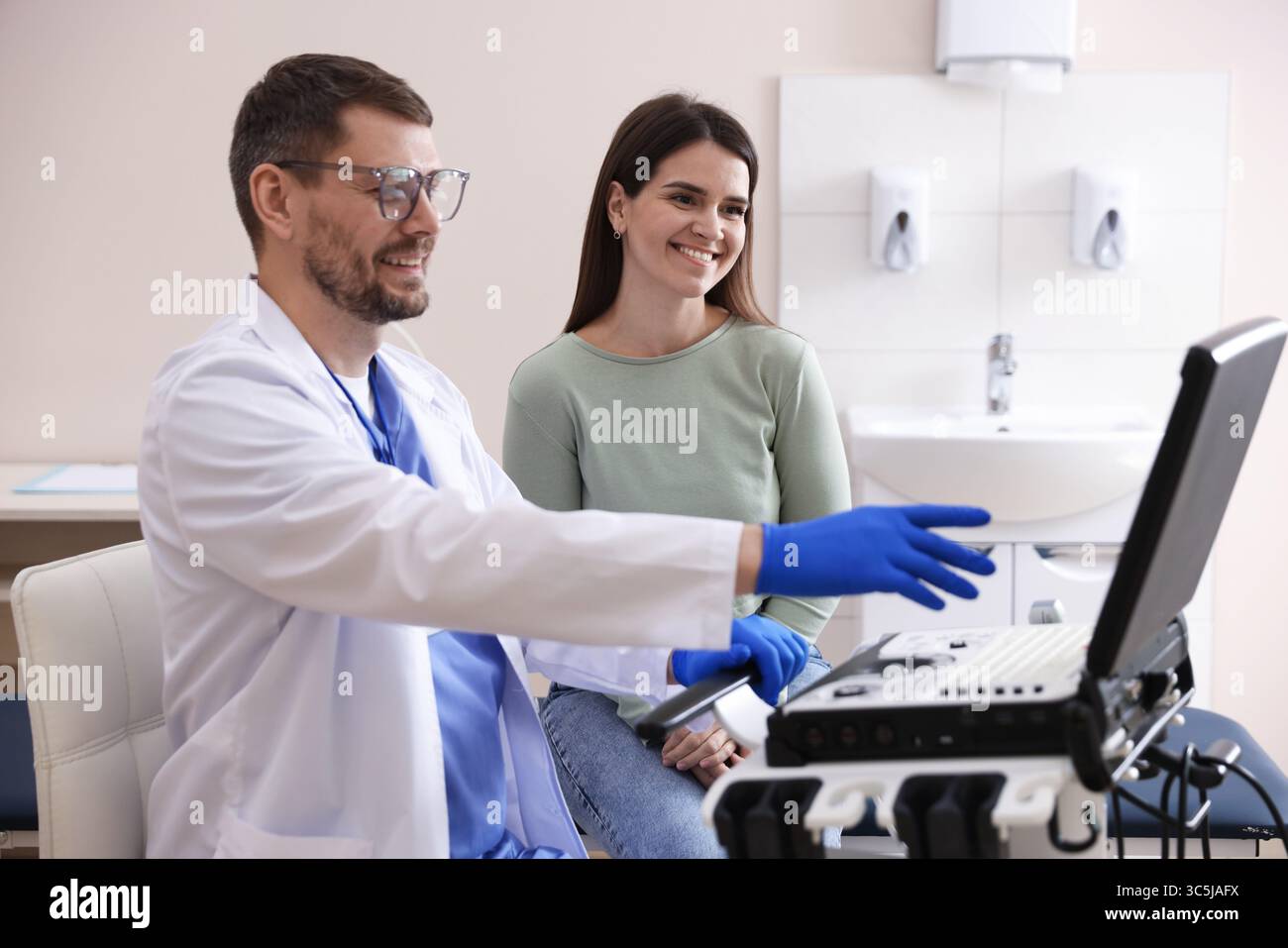 Sonographer showing woman her ultrasound imaging on screen in clinic ...