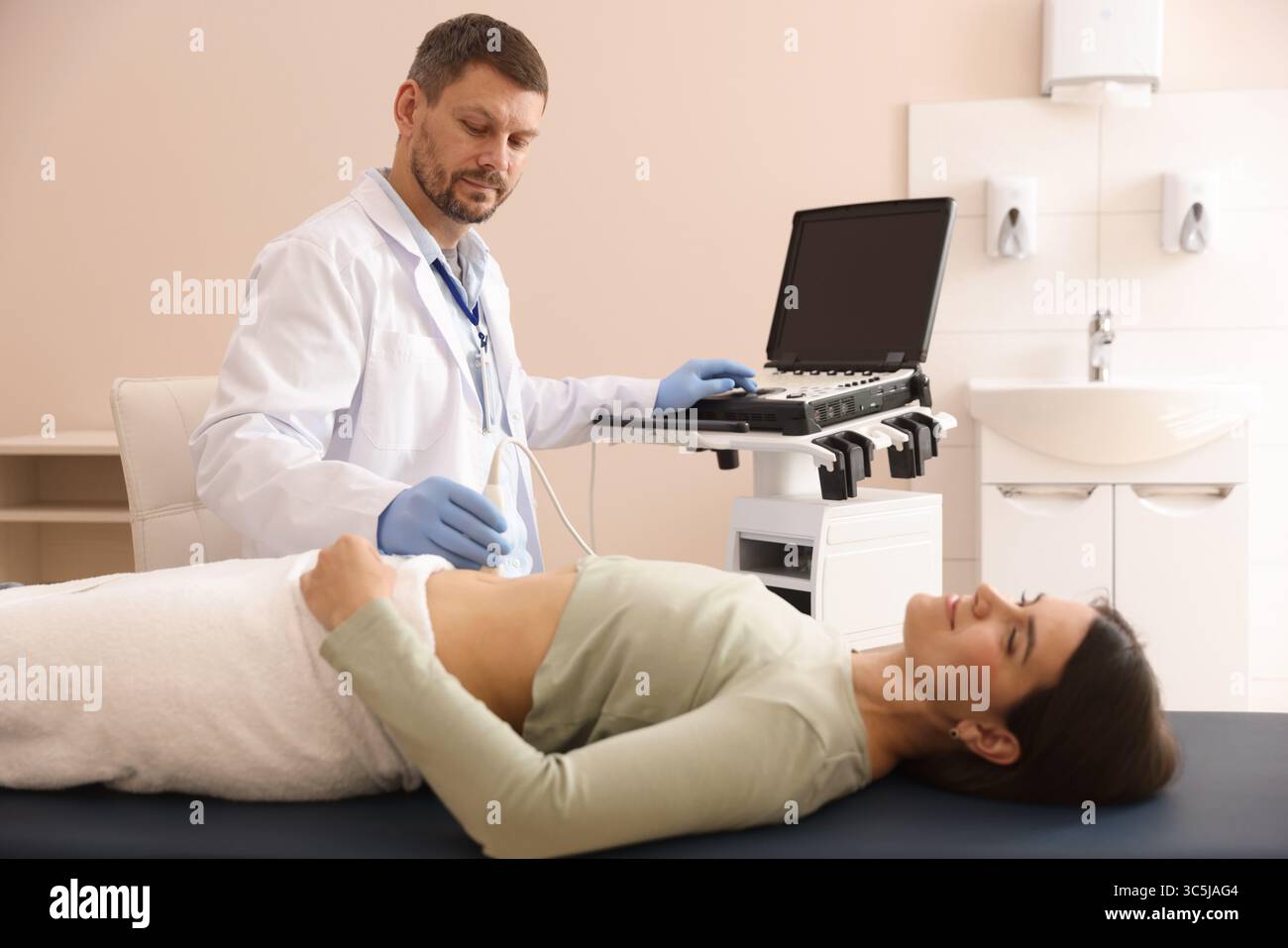 Sonographer conducting woman's abdominal ultrasound examination in ...