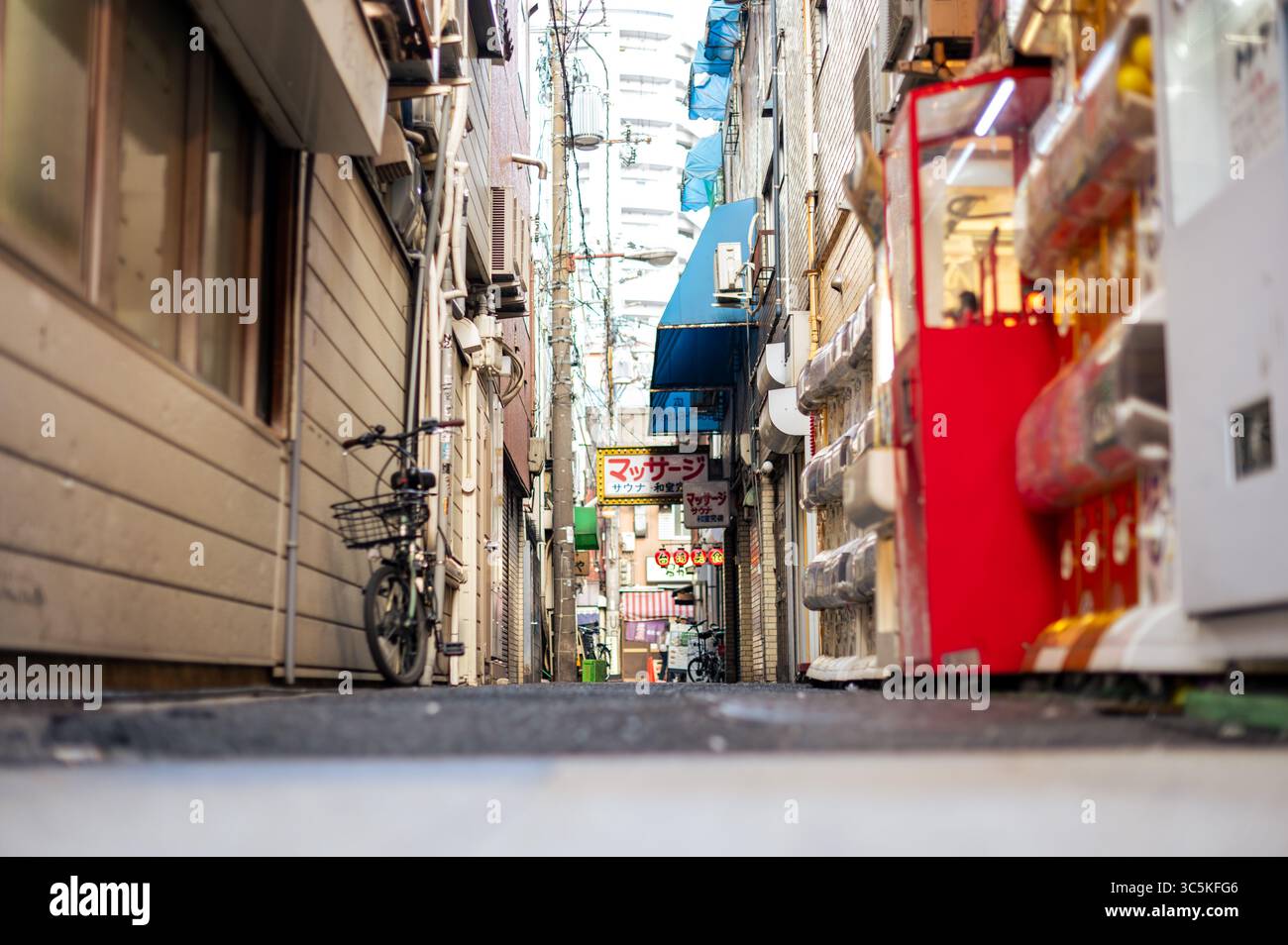 Low angle view of a narrow alley with vending machines in Osaka, Japan ...