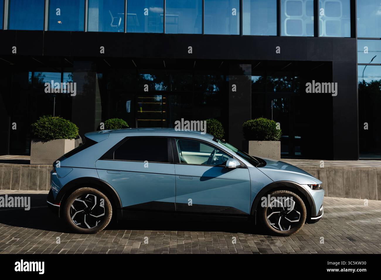 Side view of a light blue electric vehicle parked on a paved area in ...