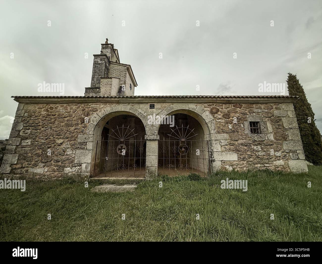 Ancient stone church featuring two arches and iron gates under cloudy ...