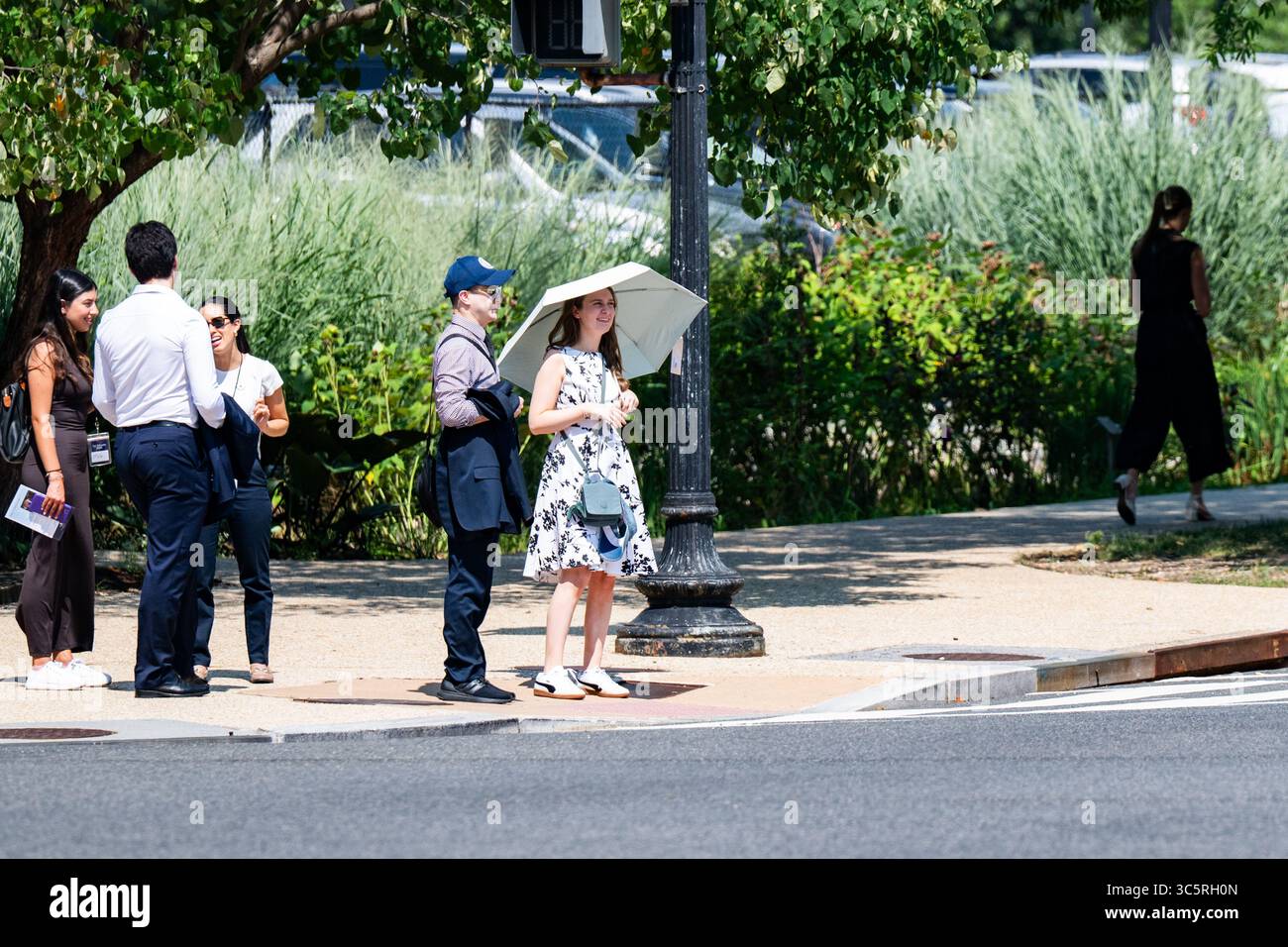 A person uses an umbrella to block the sun due to extreme heat near the ...