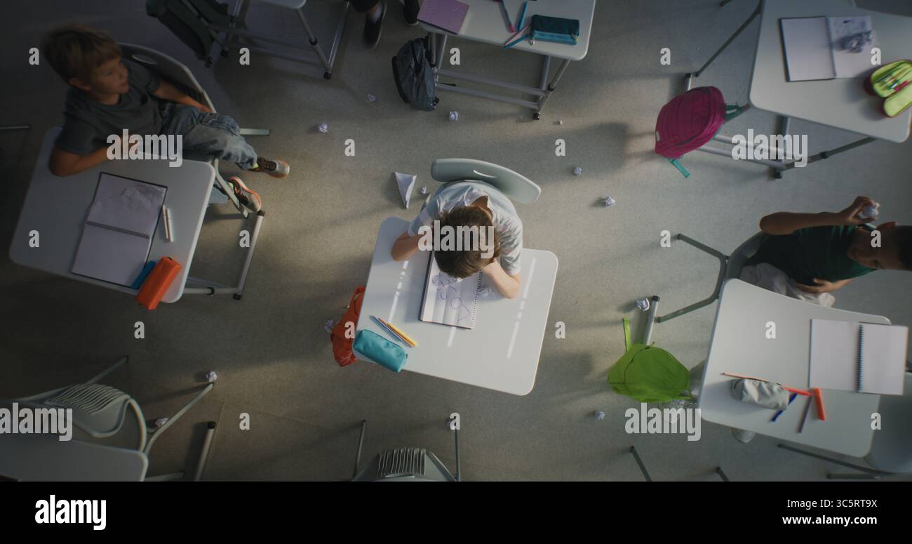 Sad Elementary School Student Sitting at Desk and Crying While ...