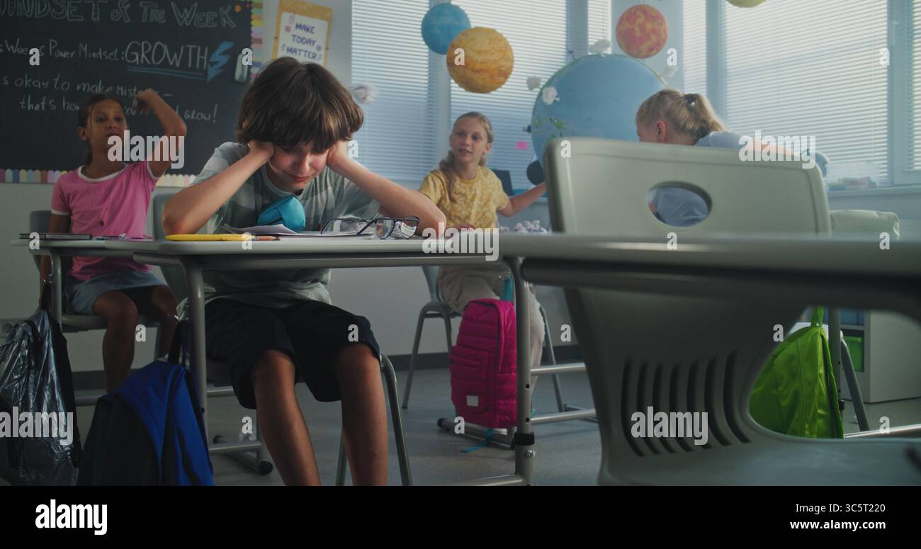 Depressed Primary School Boy Sitting Alone at Desk in Classroom While ...