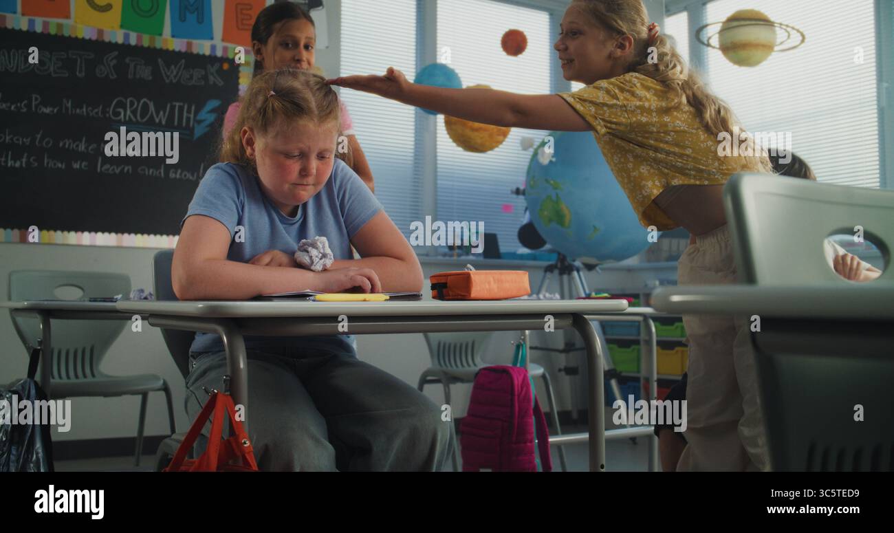 Stressed Primary School Girl Sitting Alone at Desk in Classroom While ...