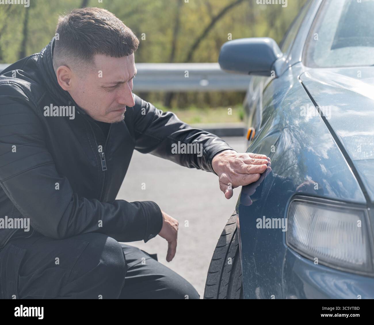 A Caucasian man inspects damage to his car Stock Photo - Alamy