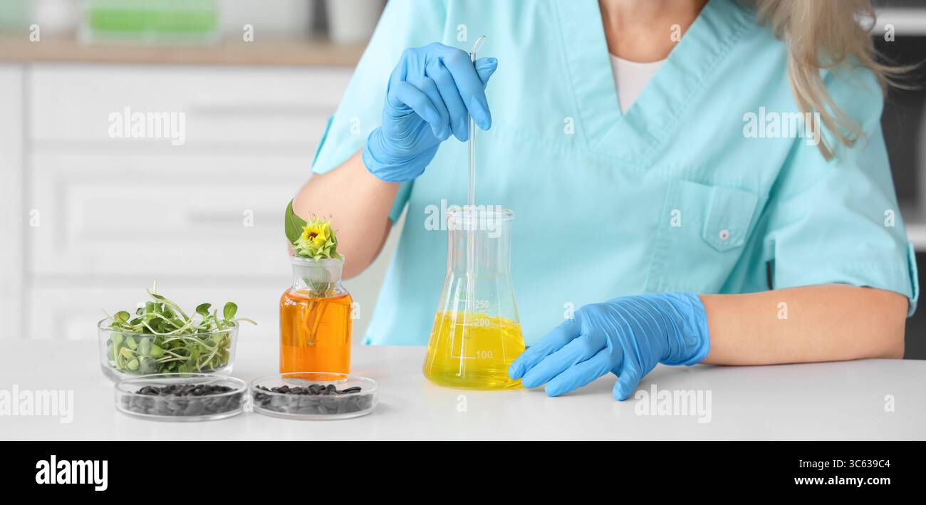 Female scientist with flask and sunflower samples working in laboratory ...