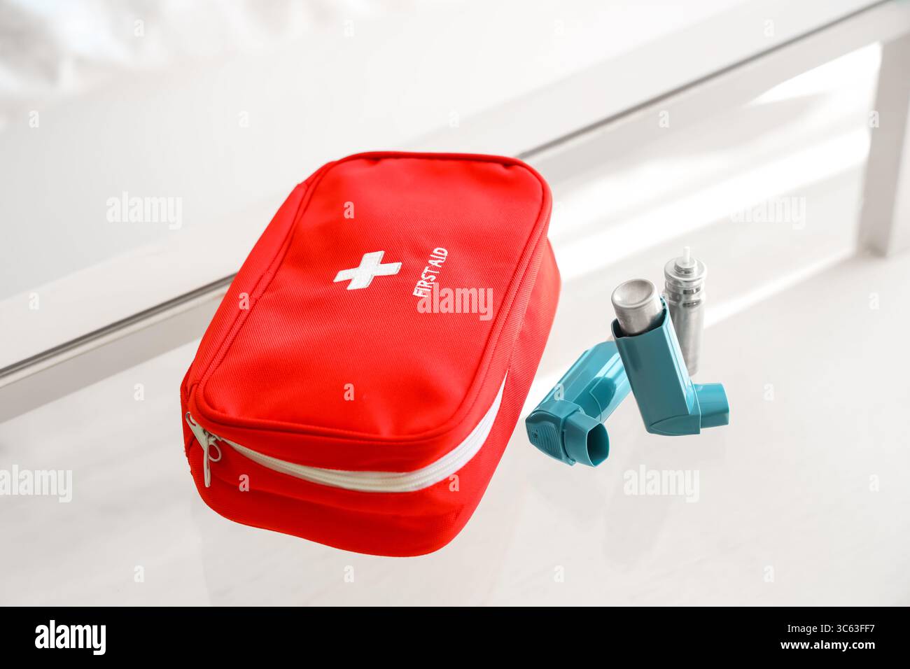 Modern inhaler, asthma aerosol canister and first aid kit on glass ...