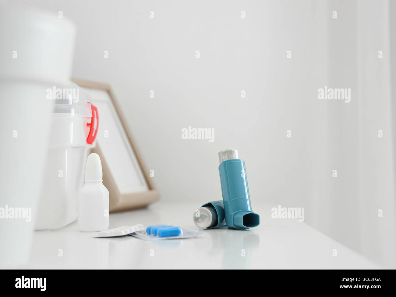 Modern inhalers, pills and first aid kit on chest of drawers, closeup ...