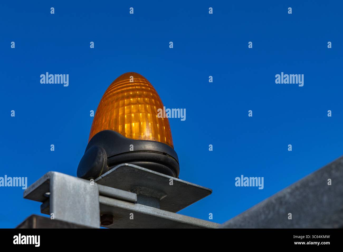 Orange warning light mounted on a metal fence, high metal fence on the ...