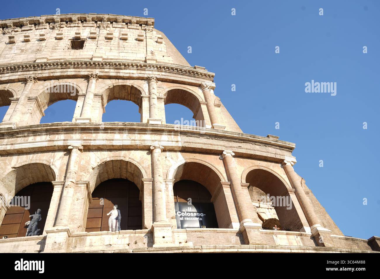 The majestic Colosseum stands under a clear blue sky, its arched ...