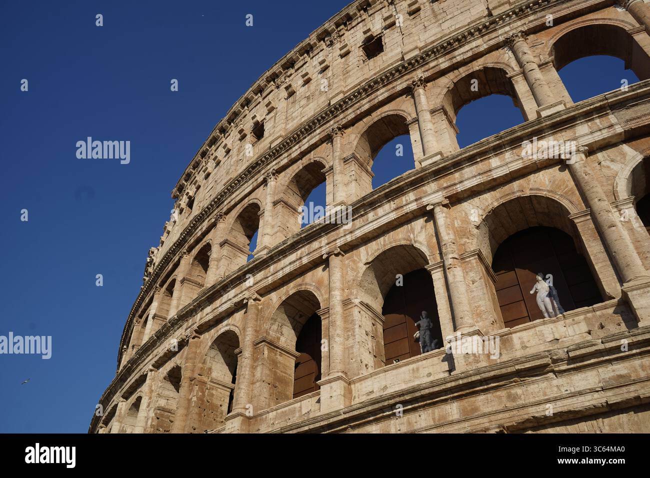 The majestic Colosseum stands under a clear blue sky, its arched ...