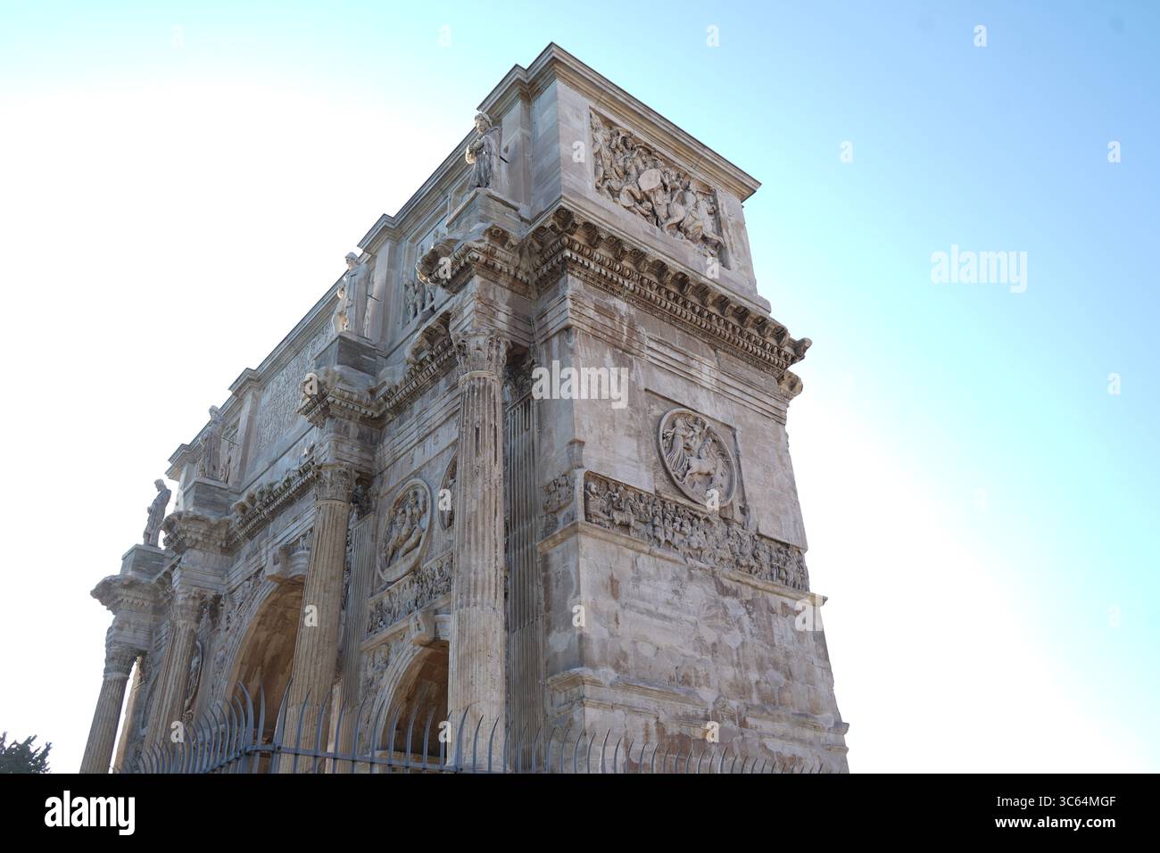 The Arch of Constantine, bathed in warm light, stands beneath a sky ...