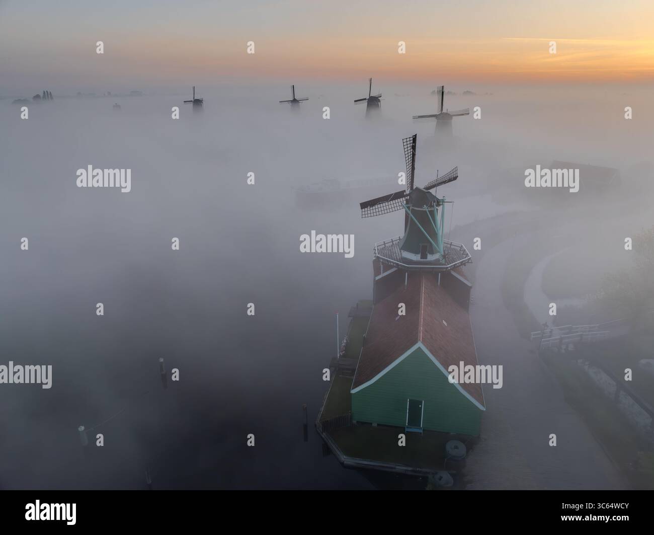 Aerial view of windmills piercing through the dense fog, their ...