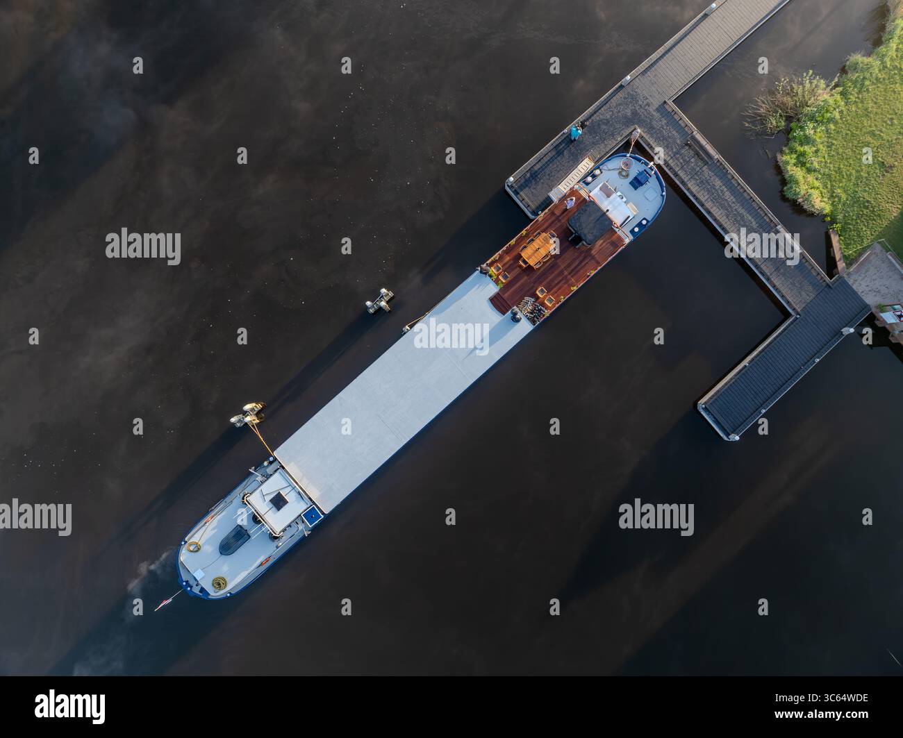 Aerial view of a barge on the inky water besides the dark wooden dock ...
