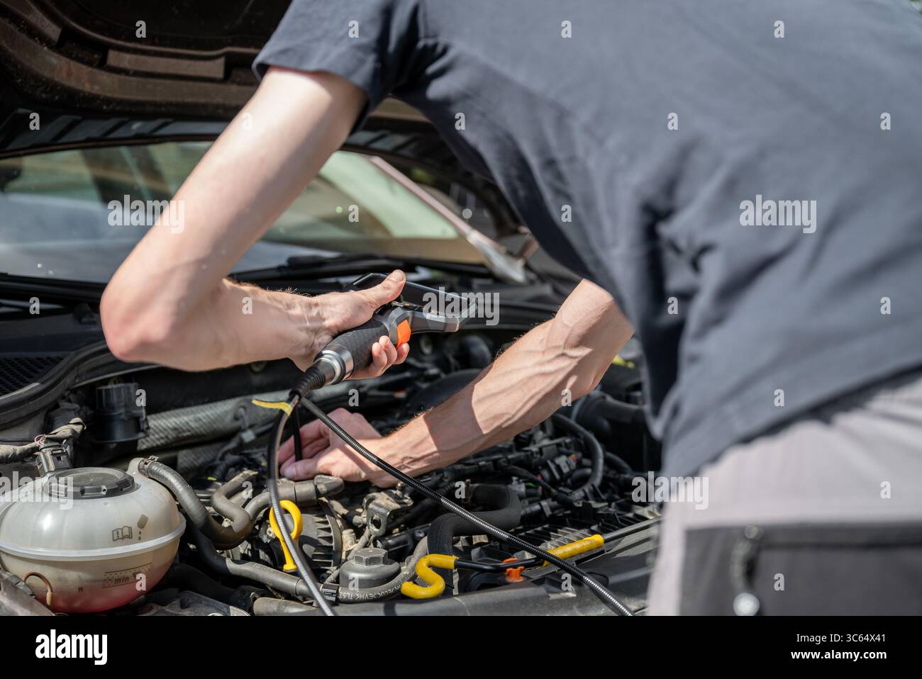 Mechanic using diagnostic tool to inspect car engine during vehicle ...