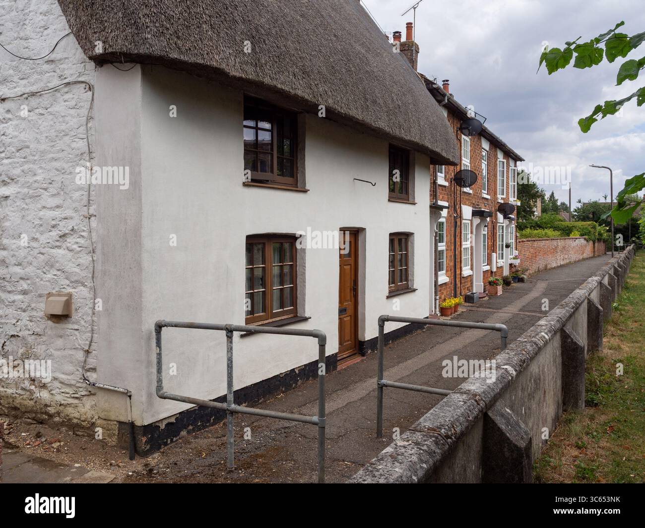 Traditional white thatched cottage beside the churchyard in Hanslope ...