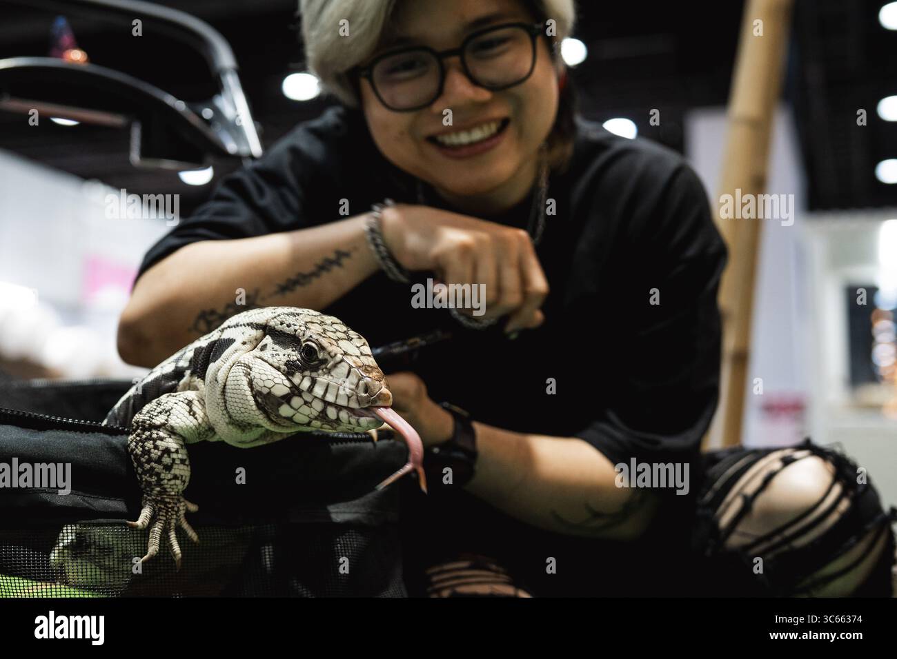 A visitor poses with a black and white tegu lizard during the Pet Expo ...
