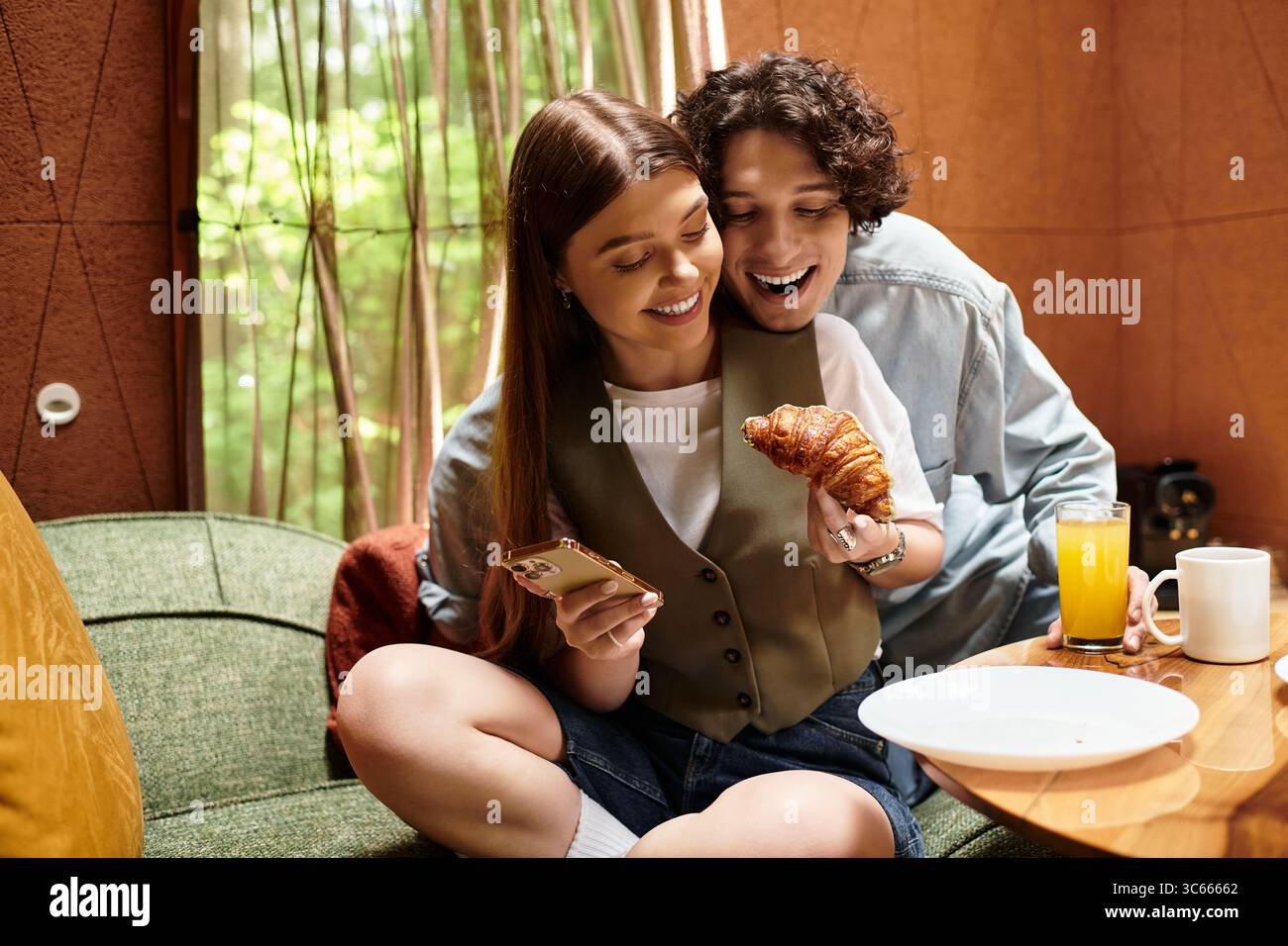 Loving couple relaxes on a comfortable couch while sharing breakfast ...