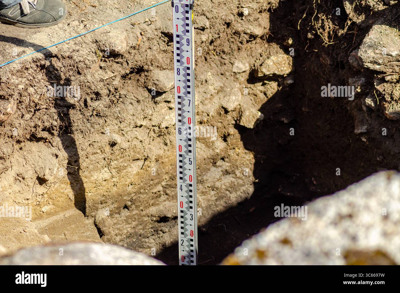 An archaeological leveling staff measuring the depth of an excavation ...