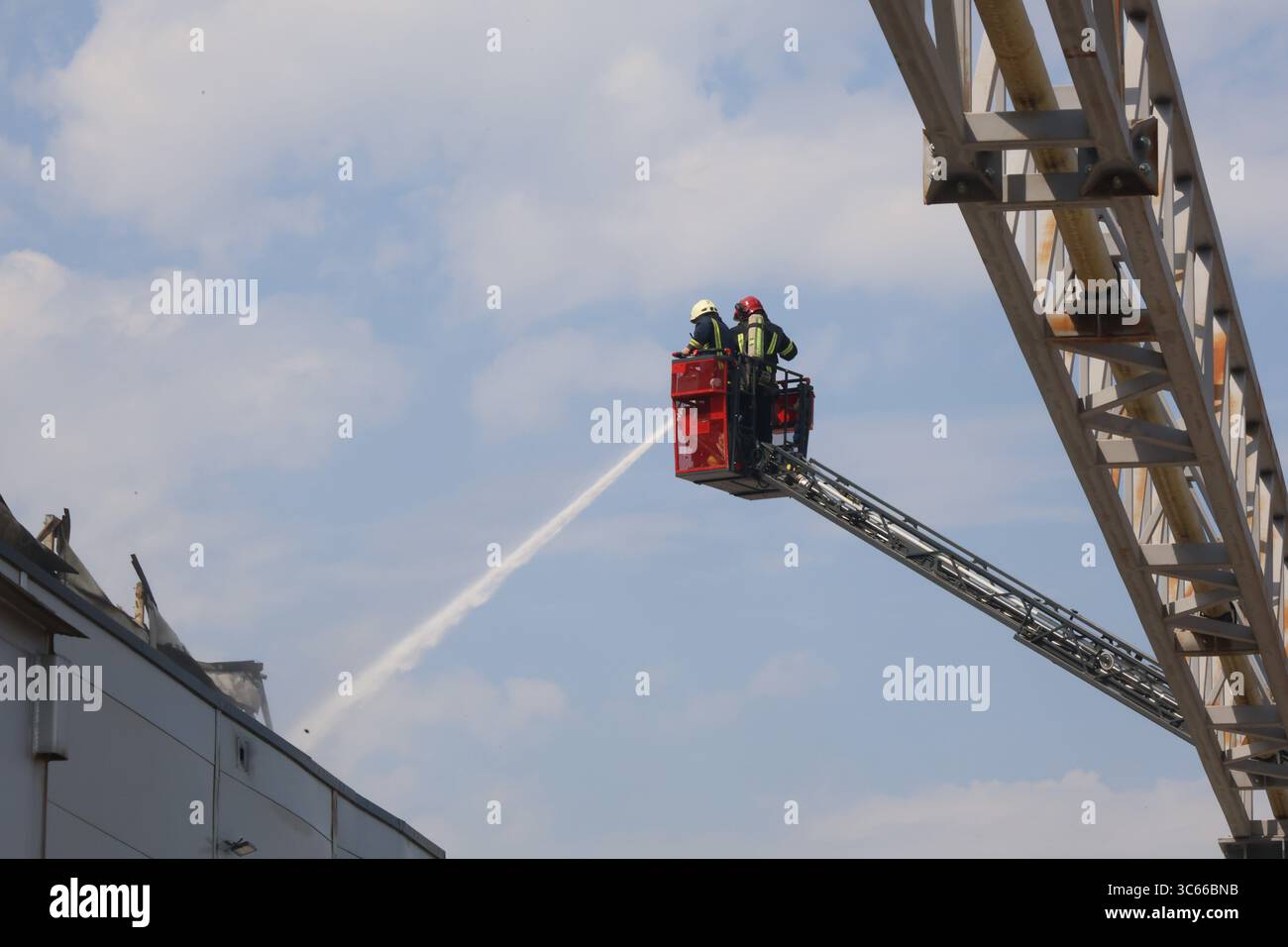 Rescuers in the cradle on top of a turntable ladder suppress a fire at ...