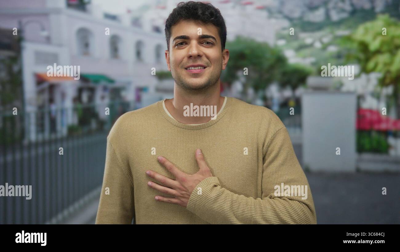 Man lifts hand placing it on chest using palm in outdoor hispanic young ...