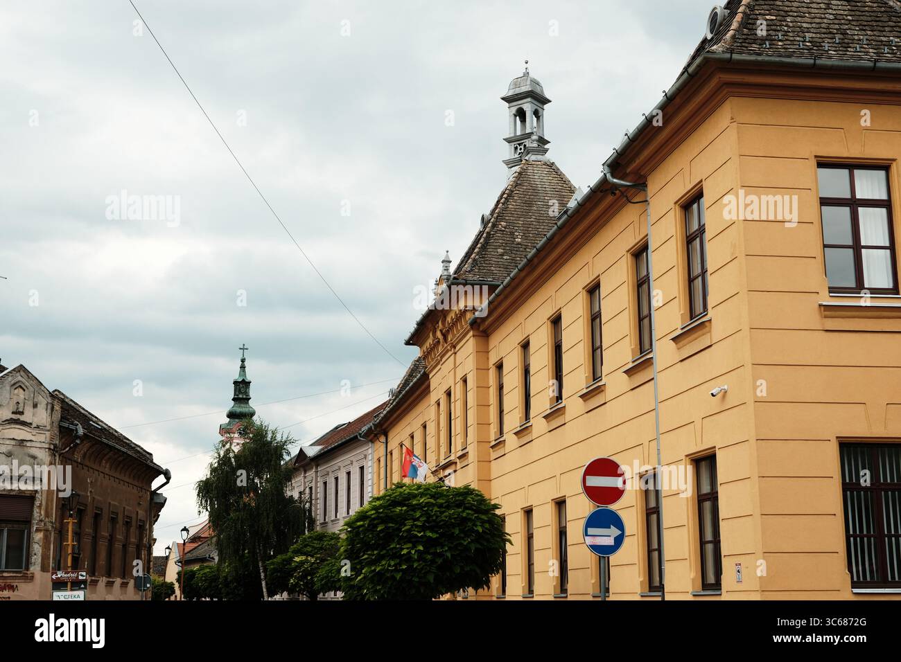 Street in small Serbian town lined with historic buildings, trees and a ...