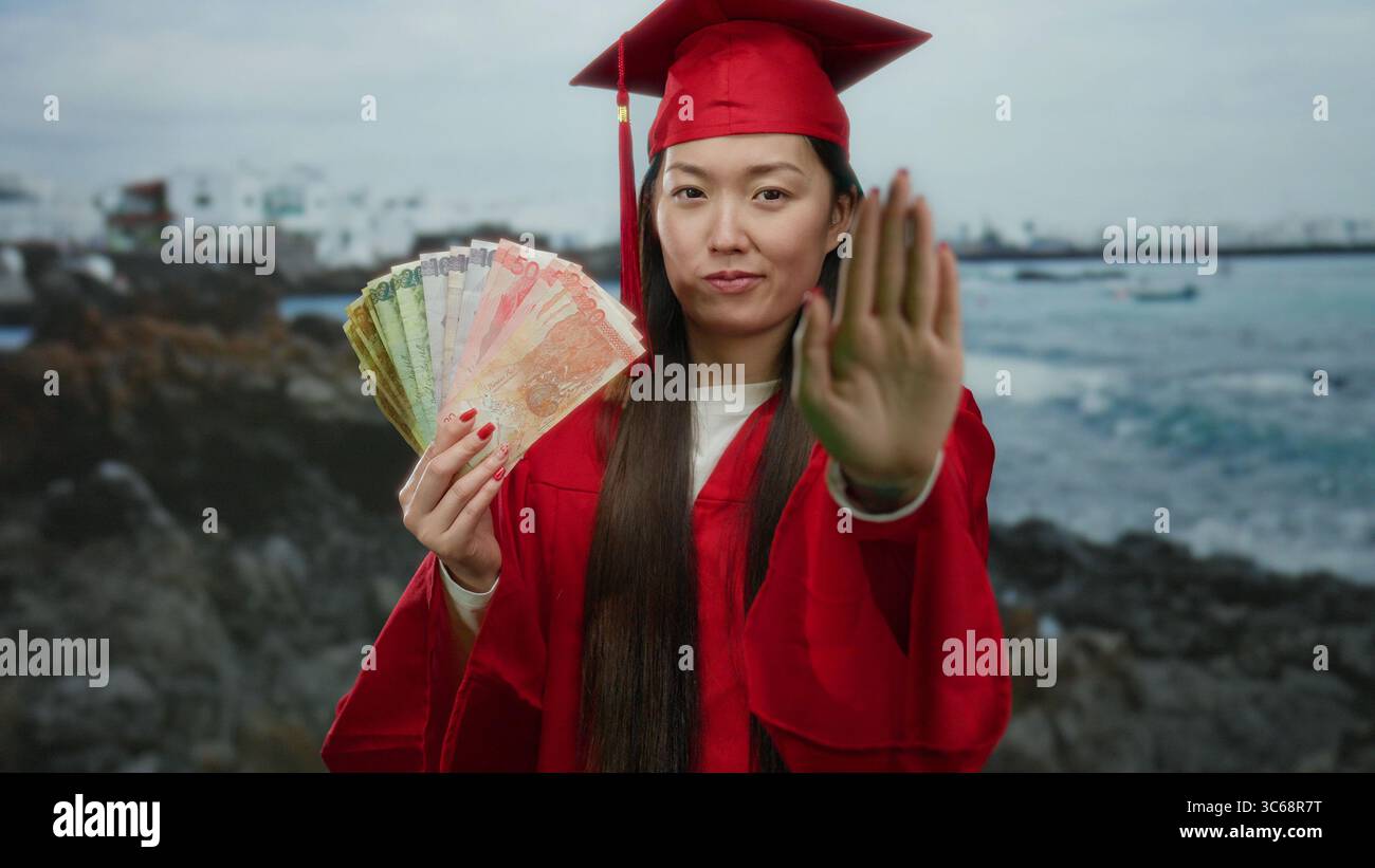 Woman in red graduation attire holding philippine peso banknotes near ...