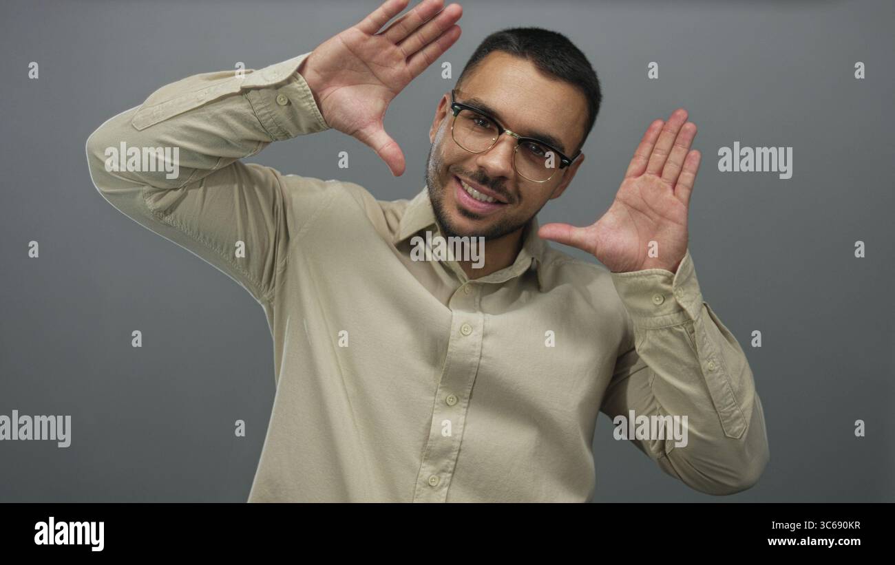 Man smiling with wide grin and forming frame with hands in gray studio ...