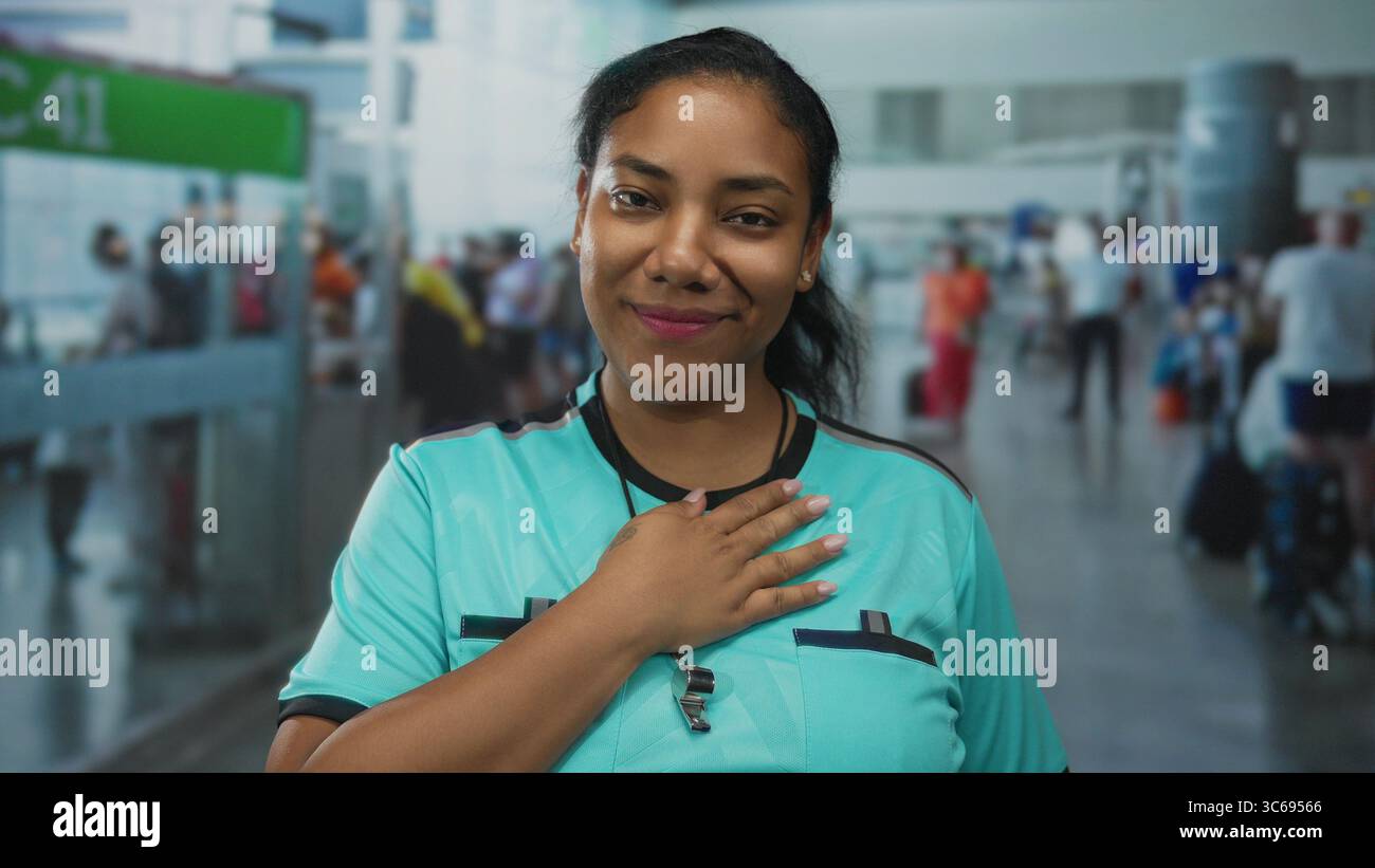 Woman referee in turquoise uniform smiling with whistle and hand on ...