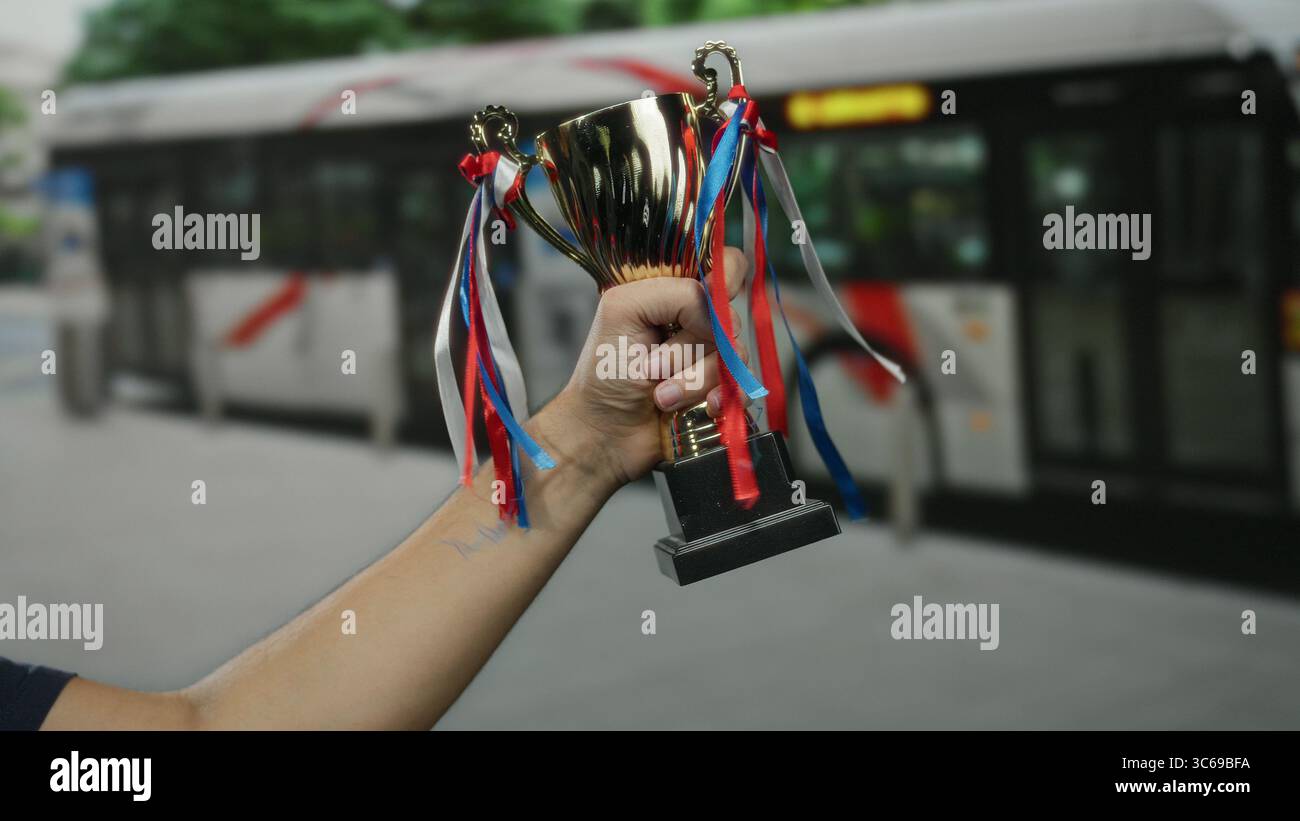 Man holding trophy with ribbons on a city bus stop background ...