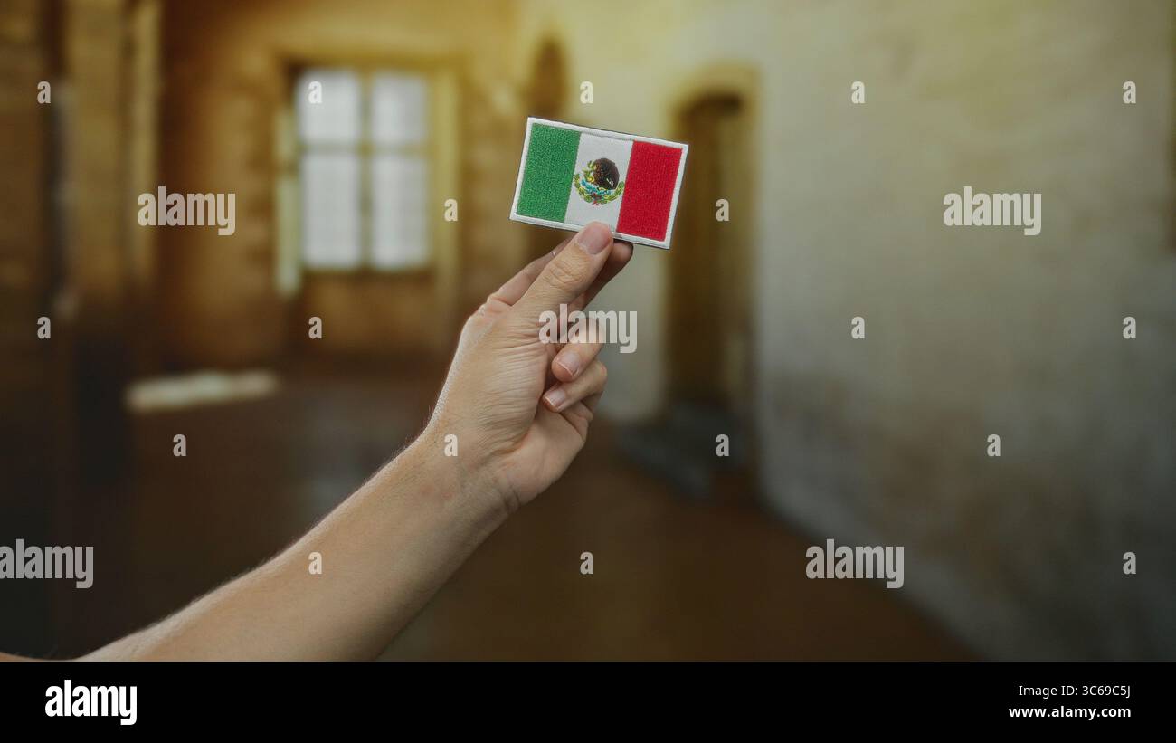 Hand holding mexican flag emblem in an indoor space, highlighting ...