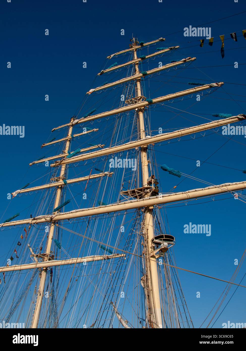 Looking up at the tall masts and rigging of a historic sailing ship ...