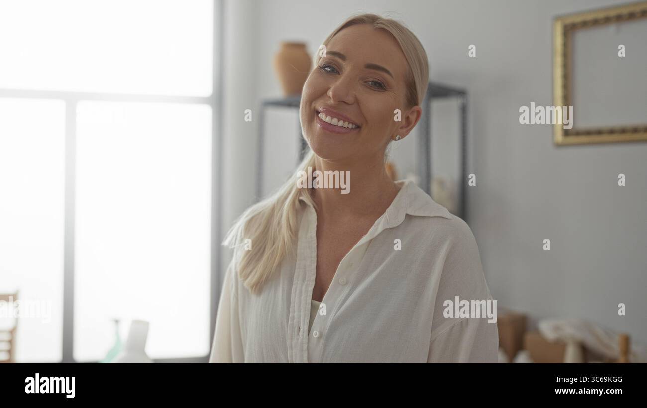 Woman smiles gently in studio under soft overhead lighting, posing with ...