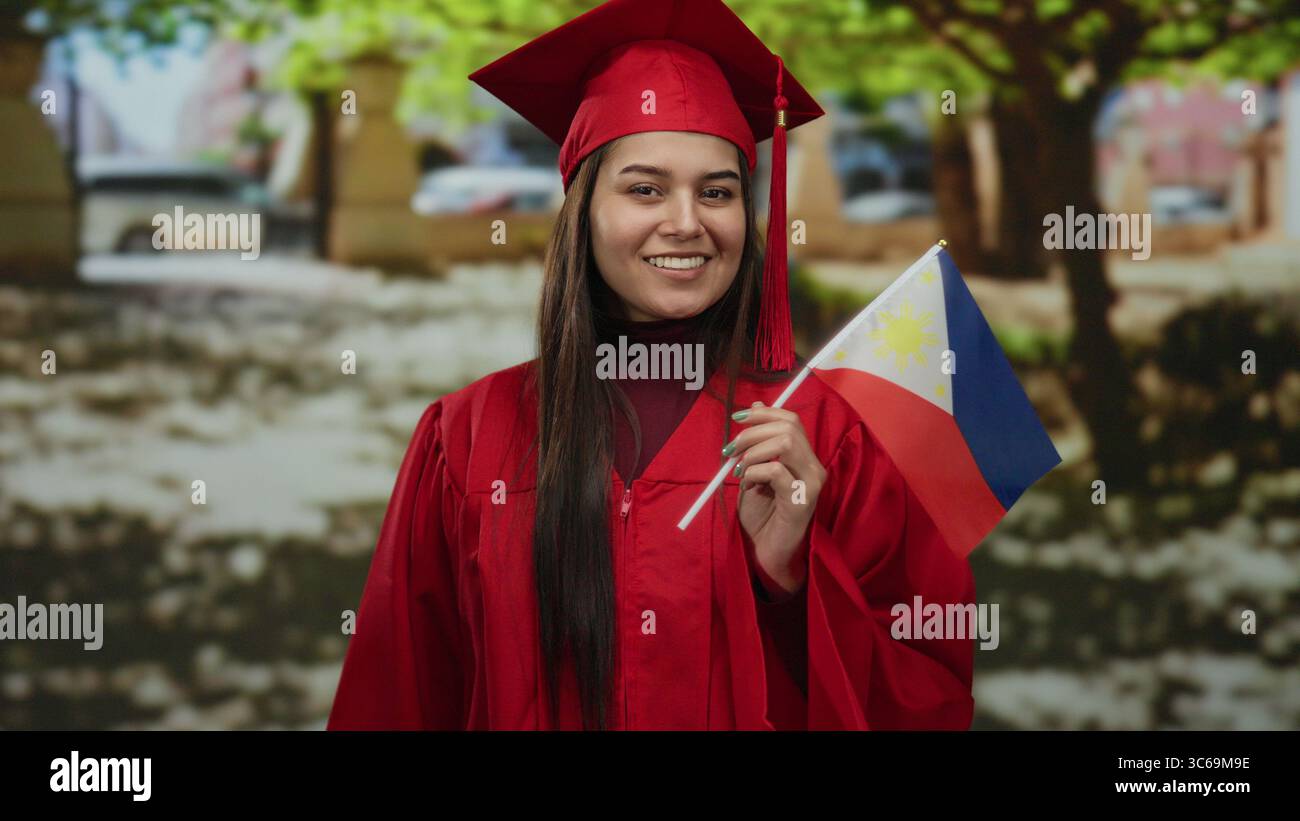 Woman in red graduation gown holding philippine flag in a park setting ...