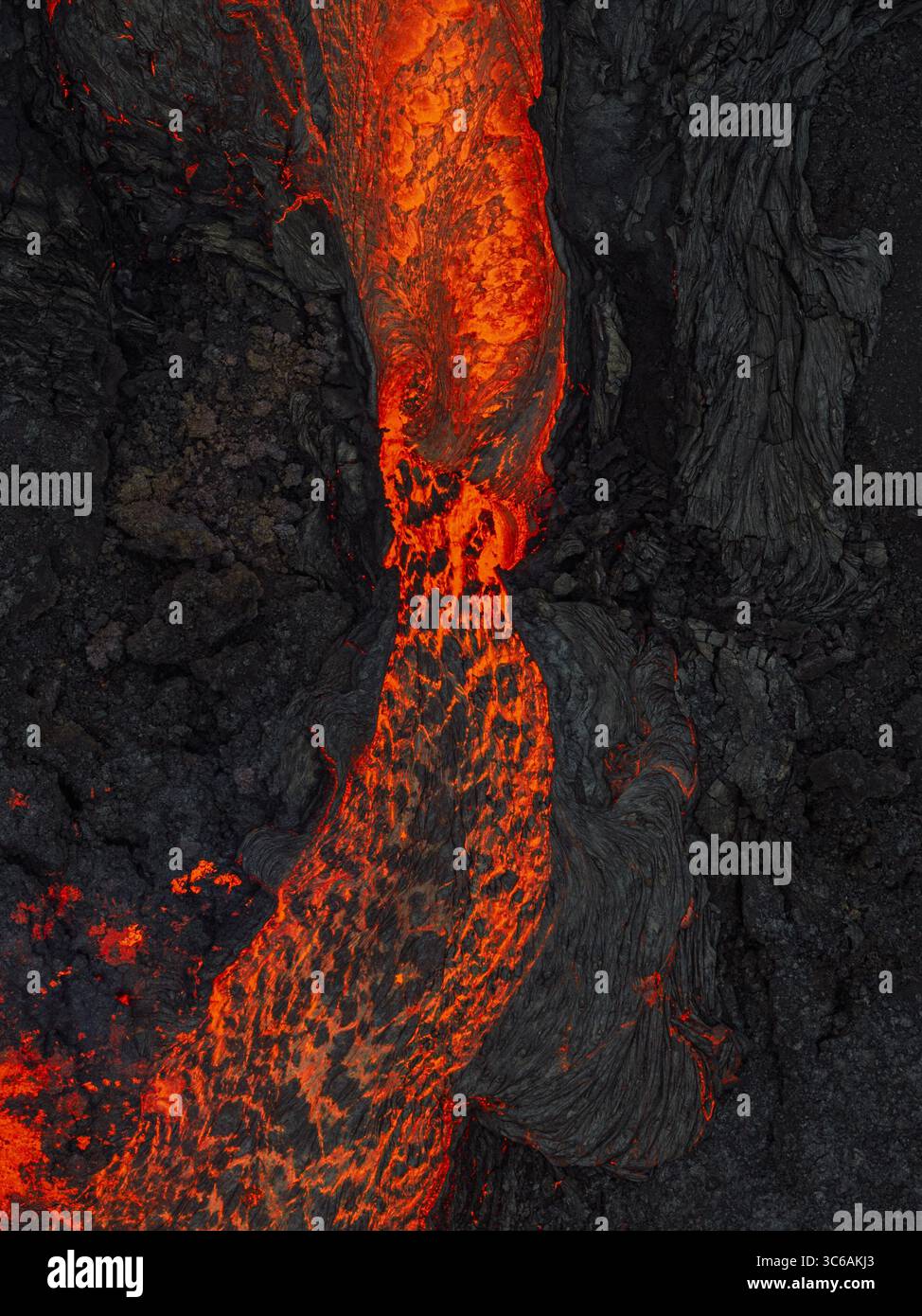 Aerial view of molten lava flowing like a fiery river through the dark ...