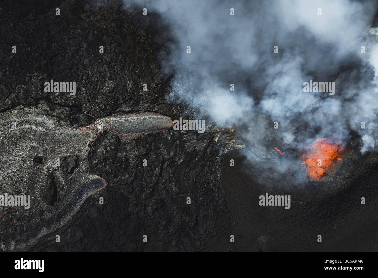 Aerial view of fiery orange lava erupting against the stark black ...