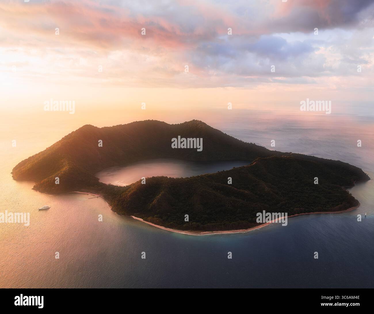 Aerial view of the volcanic island's dark, forested slopes descending ...