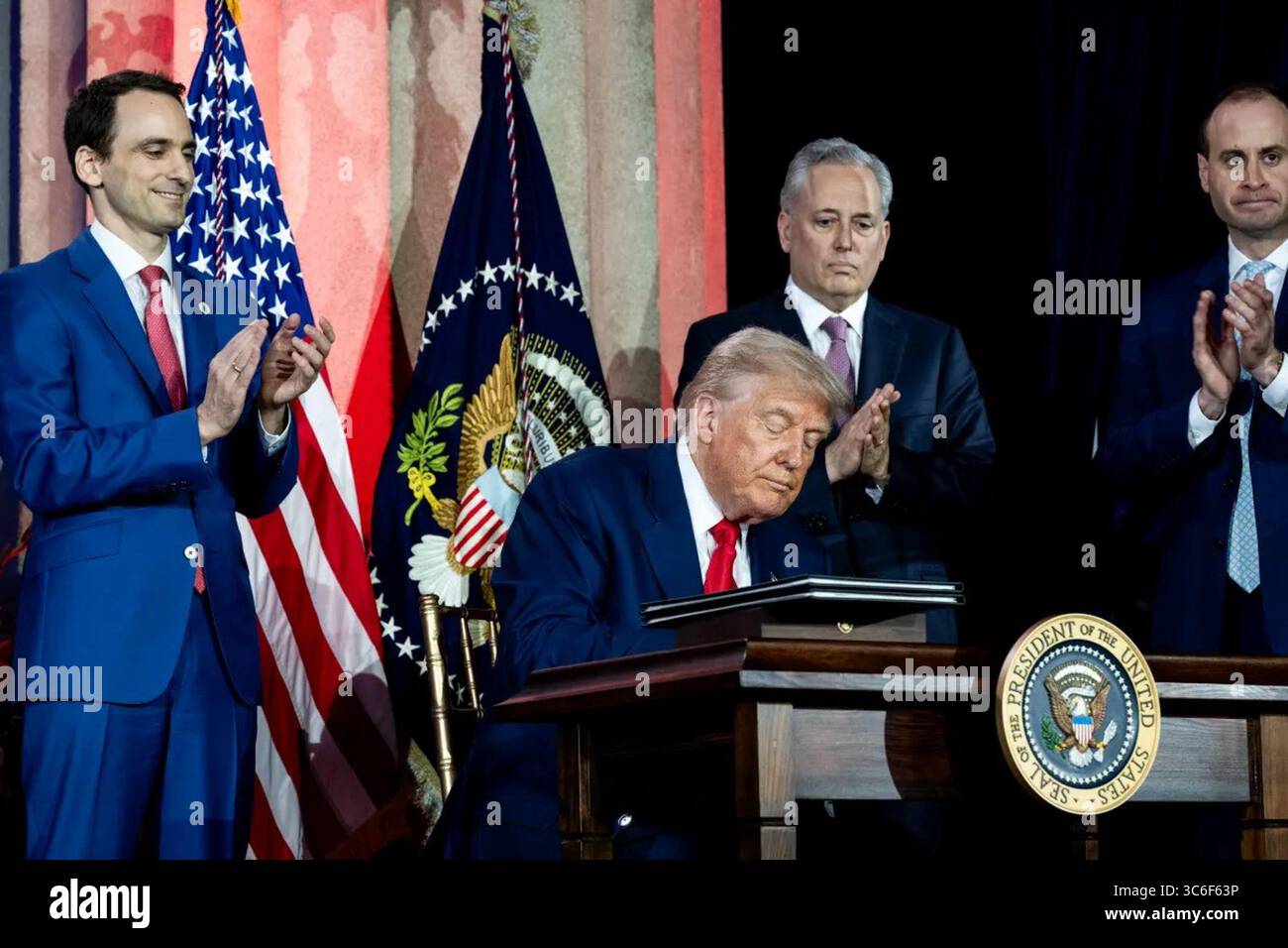 President Donald J. Trump signs an executive order as officials look on ...