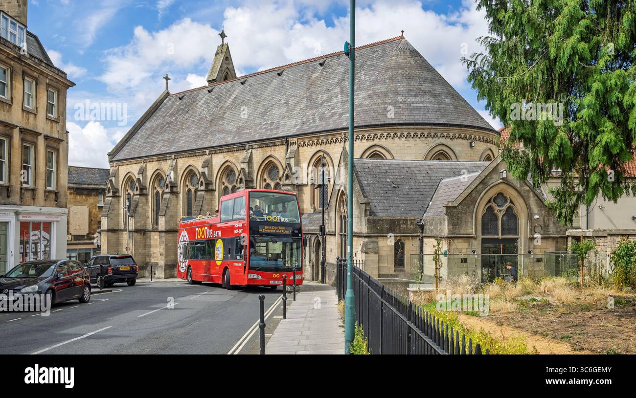 Red open top hop on hop off bus passing in front of Holy Trinity Church ...