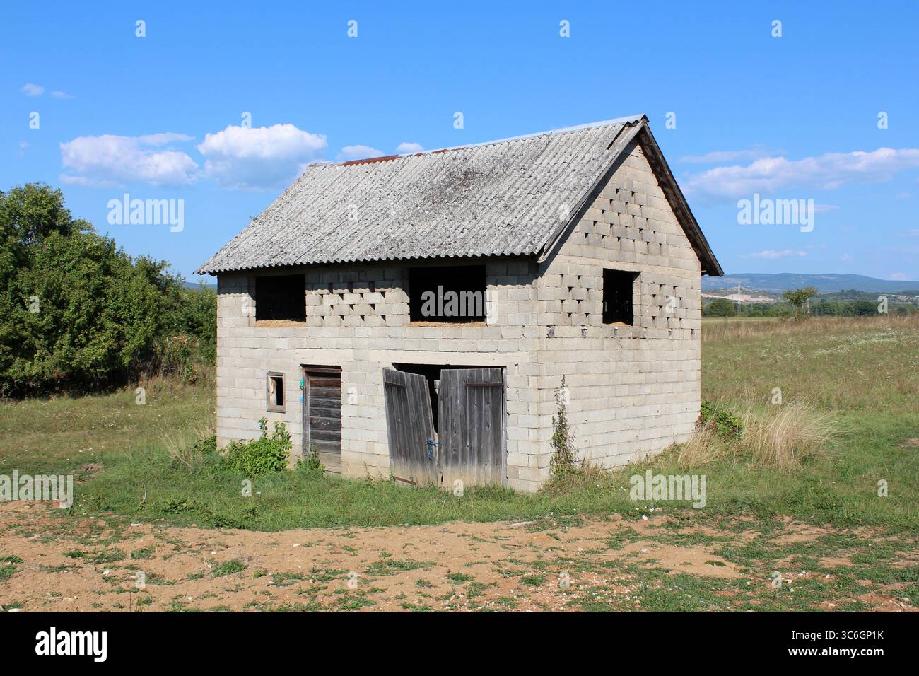 A weathered two-story barn built of cinder blocks with a corrugated ...
