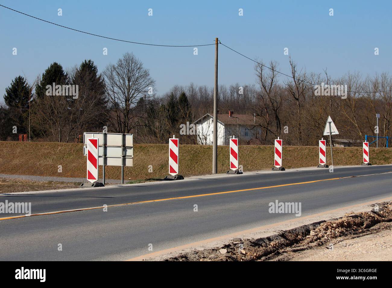 Red and white striped barriers line a paved road, temporarily narrowing ...